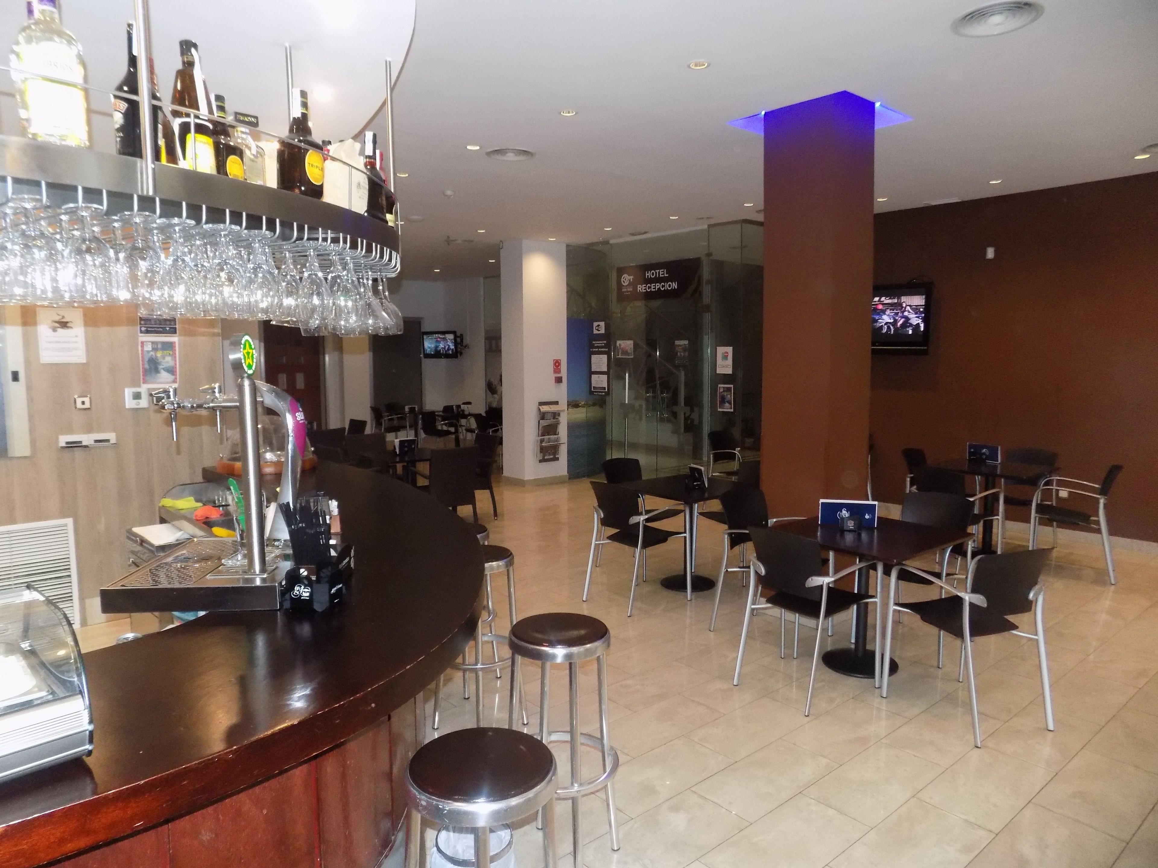 Uma área de bar com balcão, banquetas e uma tela de televisão.