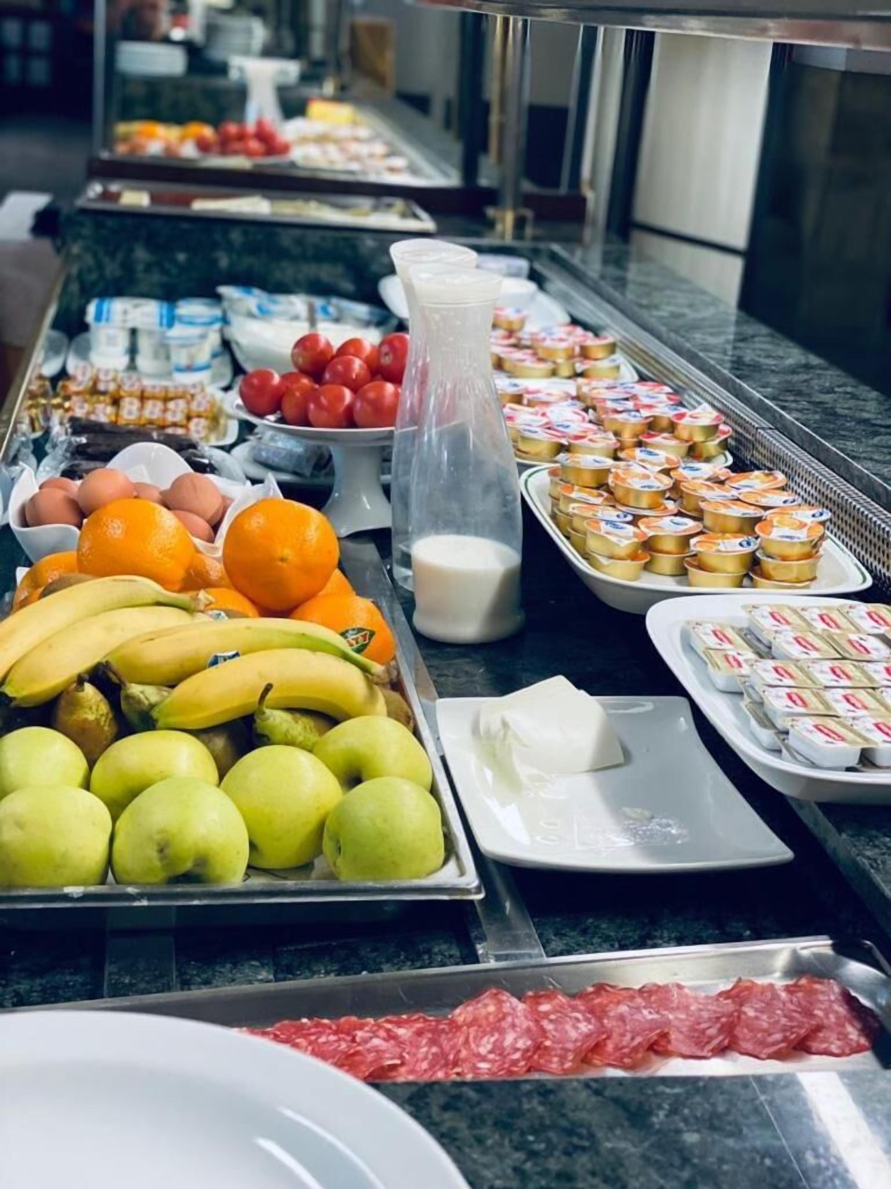 Buffet com diversos alimentos, incluindo frutas, laticínios e embutidos.