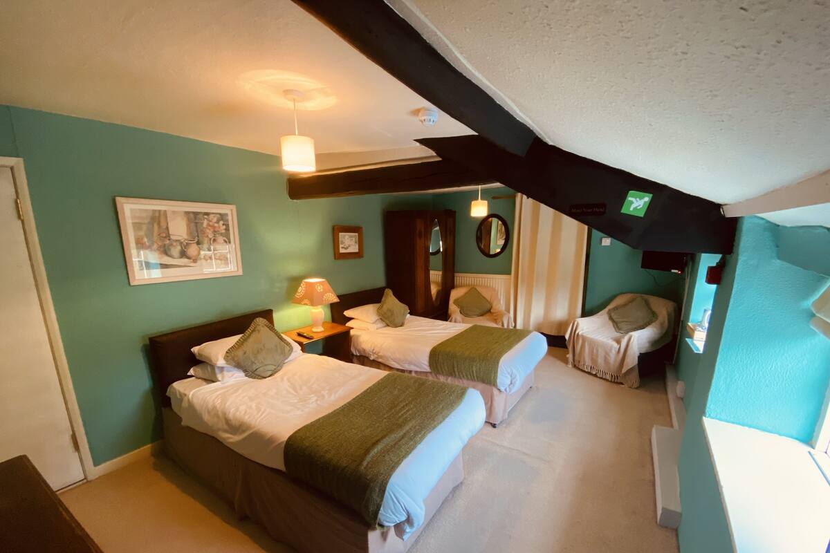 Quarto de hotel com duas camas, mesa de cabeceira com abajur, espelho e um quadro na parede.