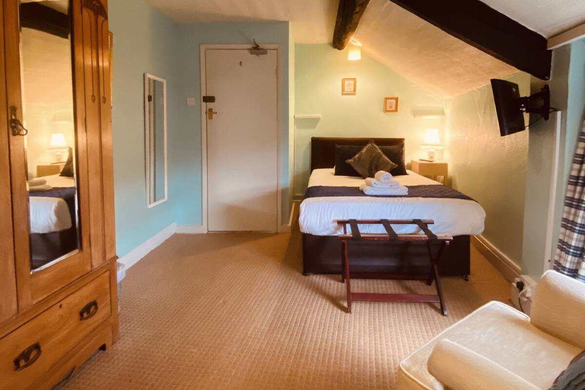 Um quarto com cama, mesa de cabeceira e guarda-roupa de madeira.