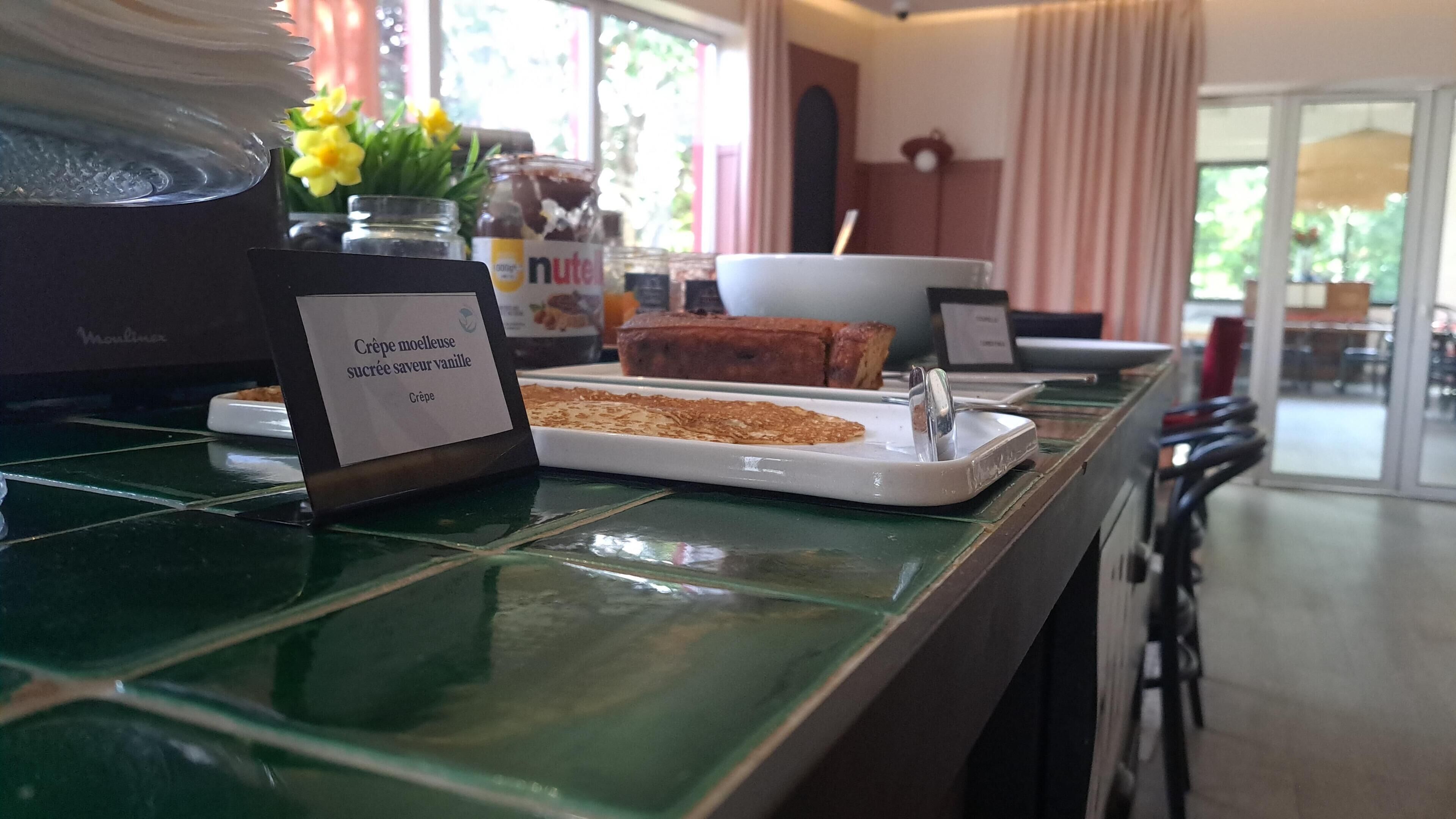 Exposição de sobremesas com um letreiro indicando uma crepe sabor baunilha, um pote de Nutella e um pão.