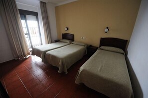 Quarto de hotel com duas camas de solteiro, uma janela grande com cortinas e chão de azulejos.
