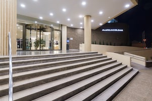 Entrada de hotel com uma escadaria curva que leva a uma área de recepção.