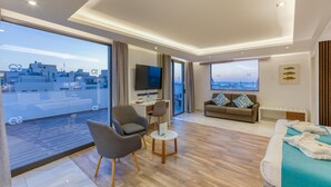 Sala de estar moderna com uma grande janela, televisão de tela plana, sofá e cama com toalhas.