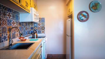 Cozinha estreita com backsplash de azulejos, pia, fogão e geladeira.