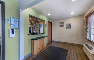 Uma área de recepção com balcão de madeira, mesa de check-in e câmera instalada na parede.