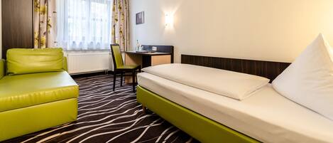Quarto de hotel com cama, escrivaninha, poltrona e sofá.