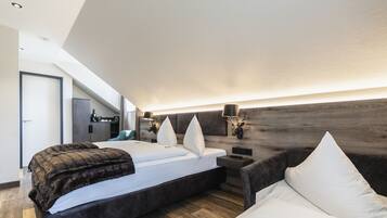 Quarto moderno com uma cama grande, mesas de cabeceira e cabeceira com luzes fixadas na parede.