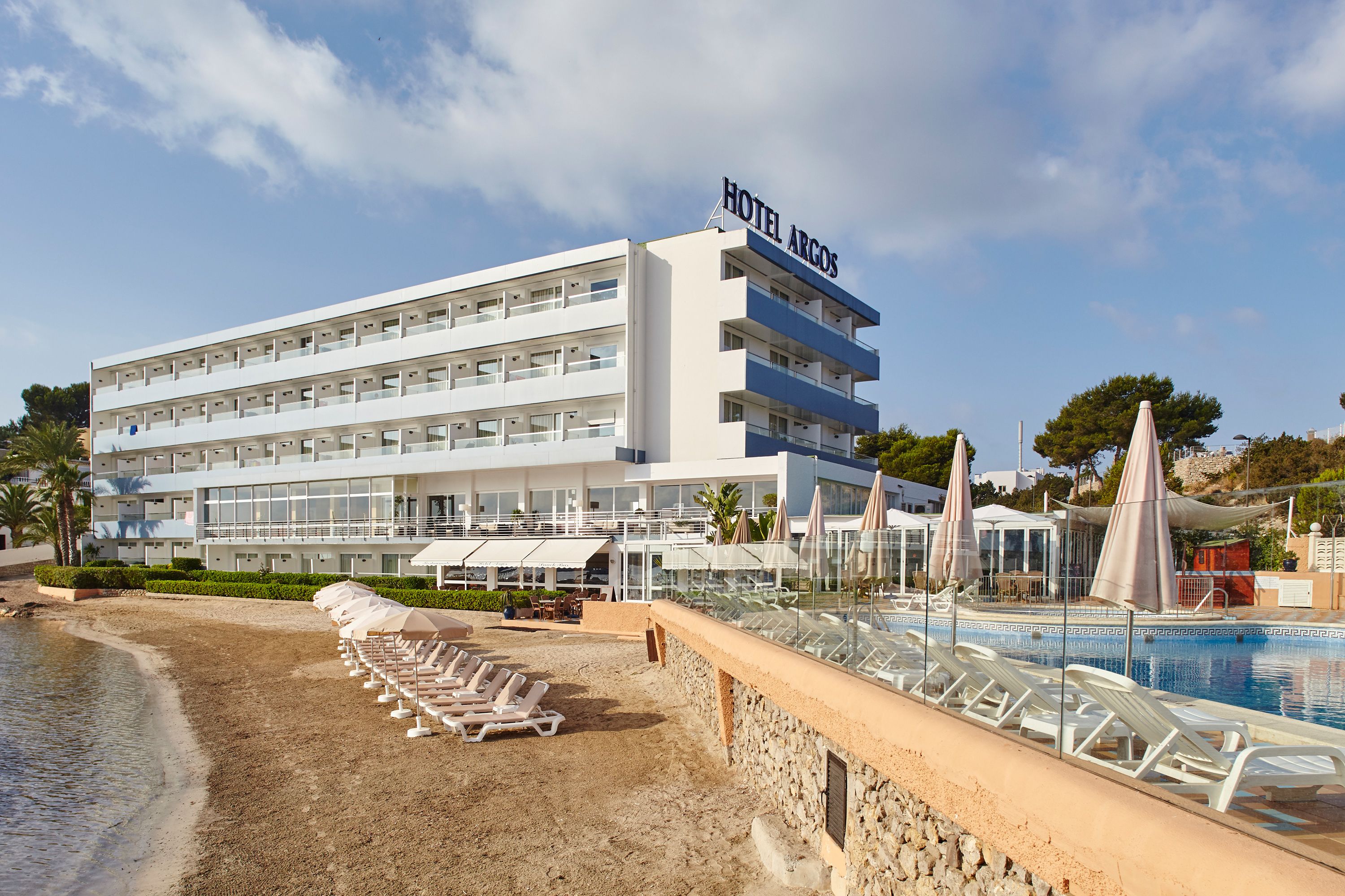 Um hotel com piscina, espreguiçadeiras e guarda-sóis.