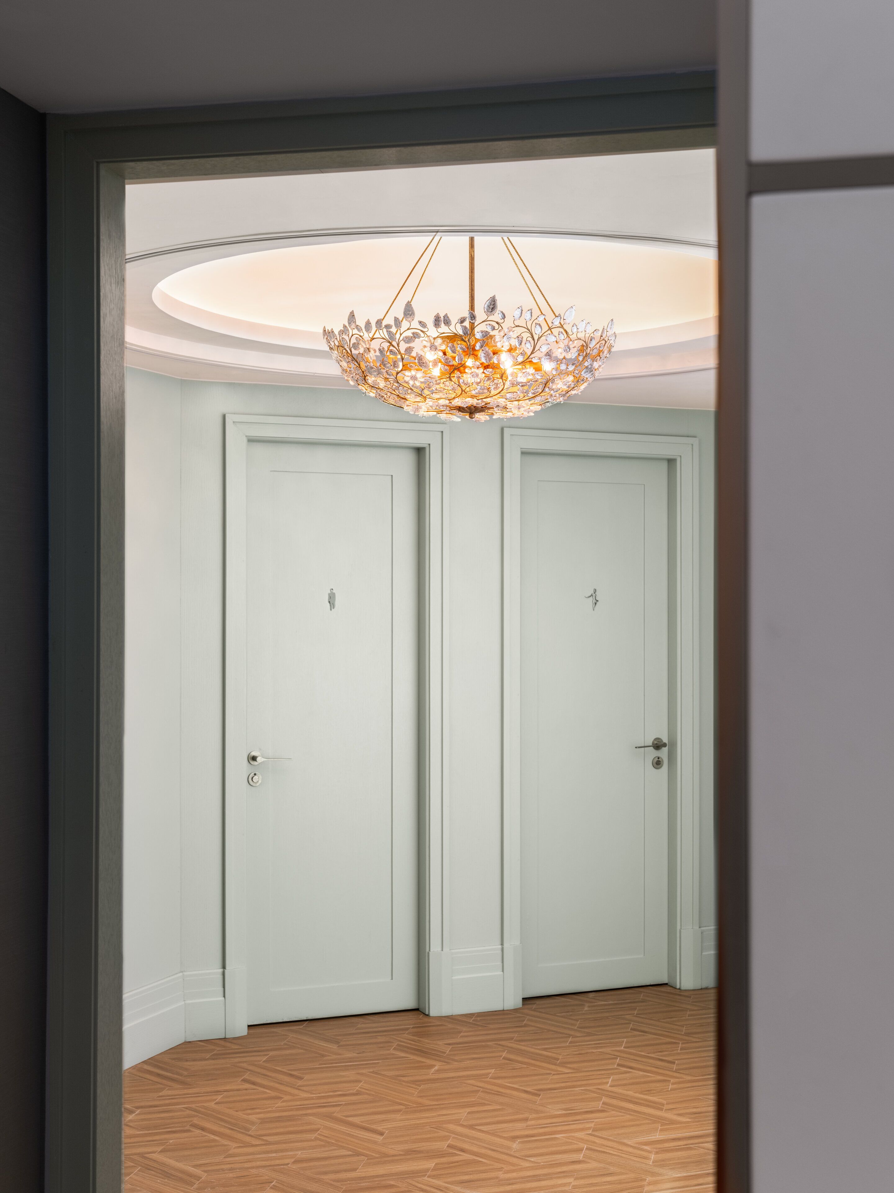Um corredor com duas portas fechadas e um candelabro.