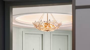 Um corredor com duas portas fechadas e um candelabro.