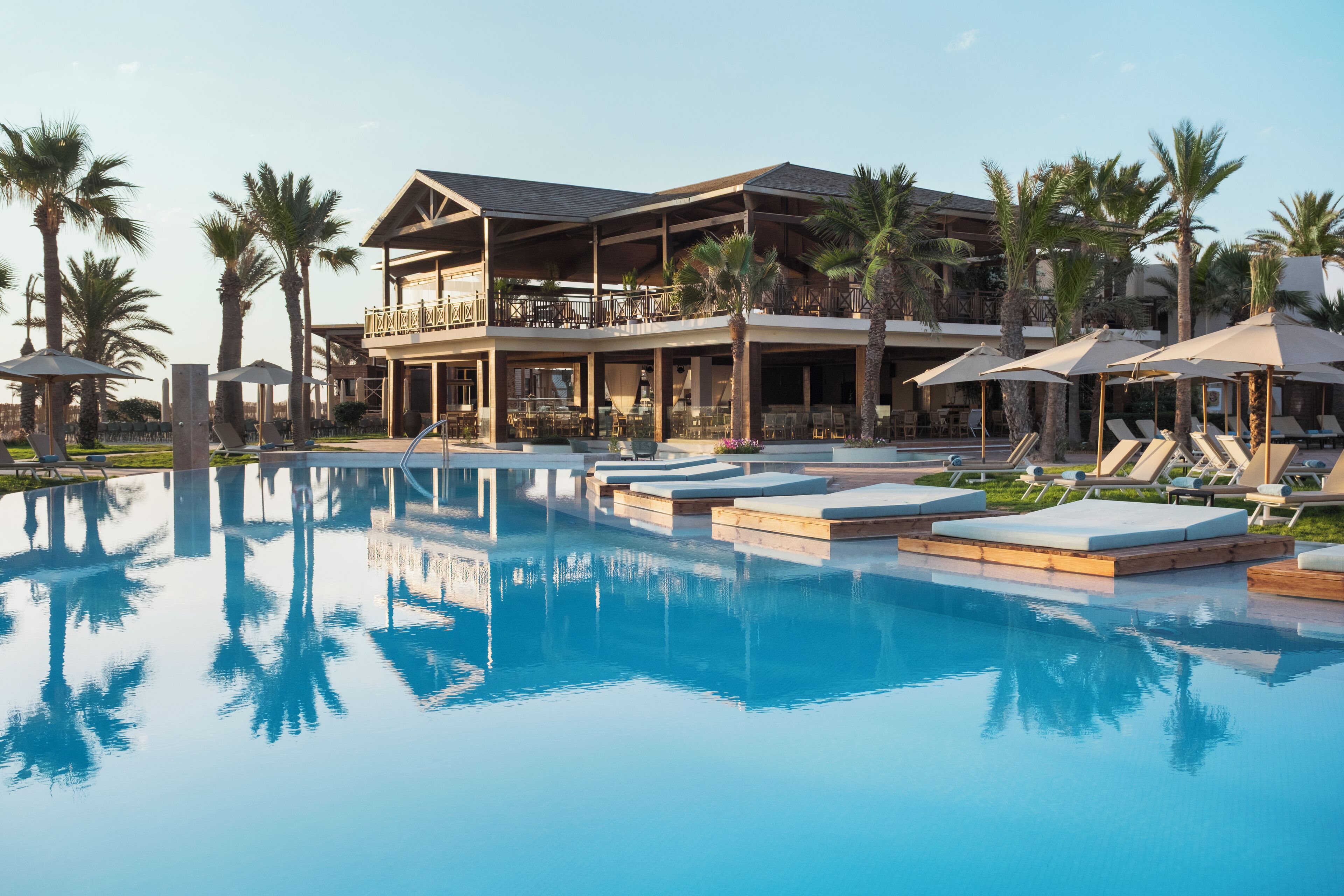 Resort com piscina, espreguiçadeiras e palmeiras.