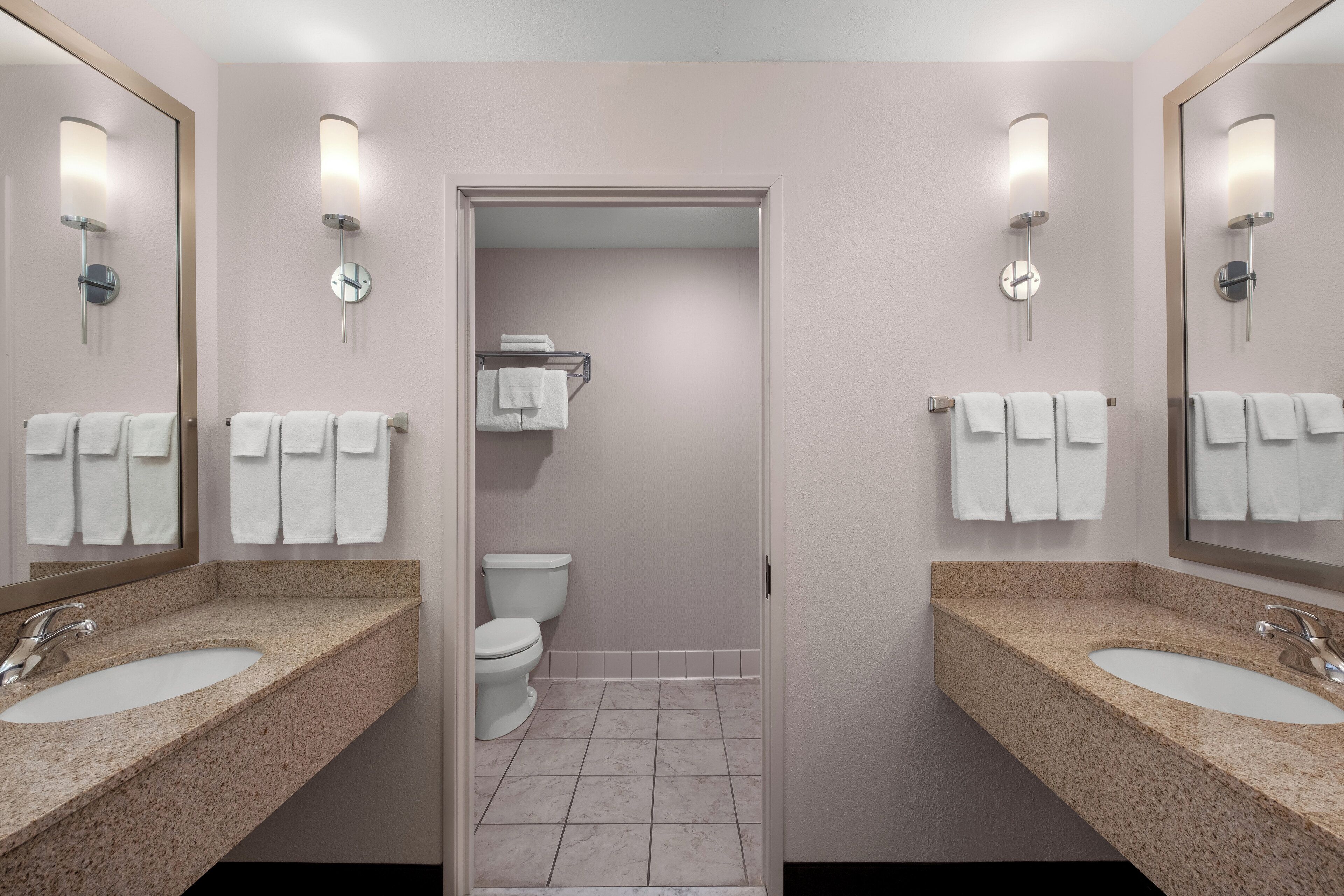 Um banheiro moderno com duas pias, vaso sanitário e chuveiro.