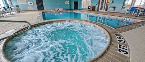 Piscina interna com área de hidromassagem, pistas demarcadas e placa de salva-vidas.