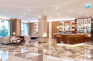 Um hall de hotel moderno com área de bar, assentos e um grande pilar.