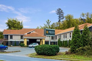 Um hotel com telhado de azulejos, estacionamento e uma placa com a inscrição "La Quinta by Wyndham".