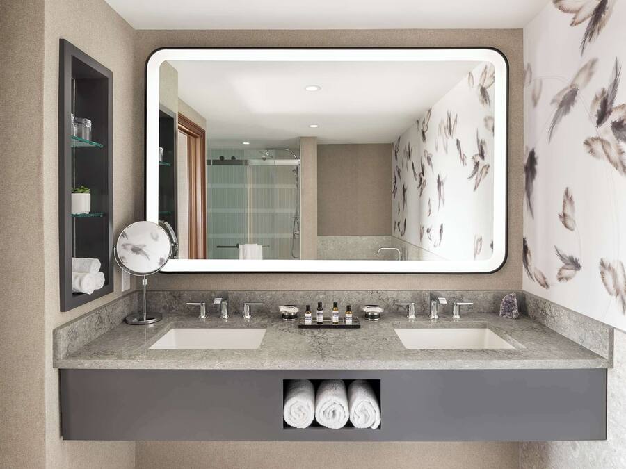 Uma casa de banho moderna com um espelho grande, duas pias e um móvel com prateleiras.