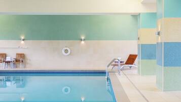 Piscina com espreguiçadeiras e parede revestida em azulejo.