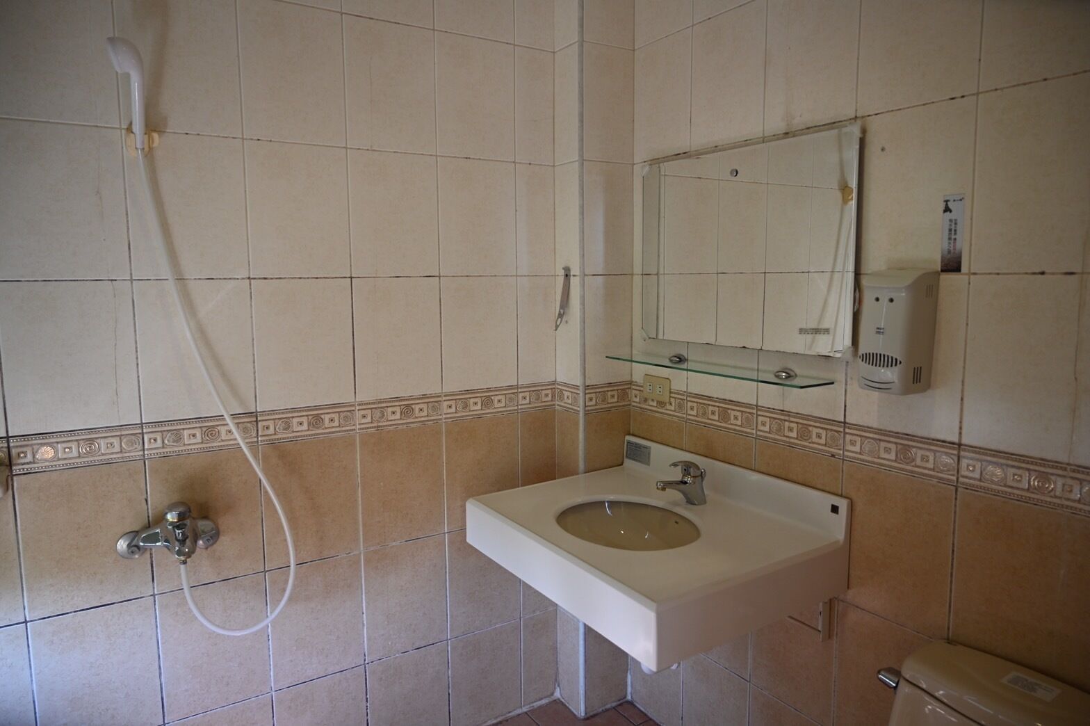 Casa de banho com lavatório, espelho e chuveiro.