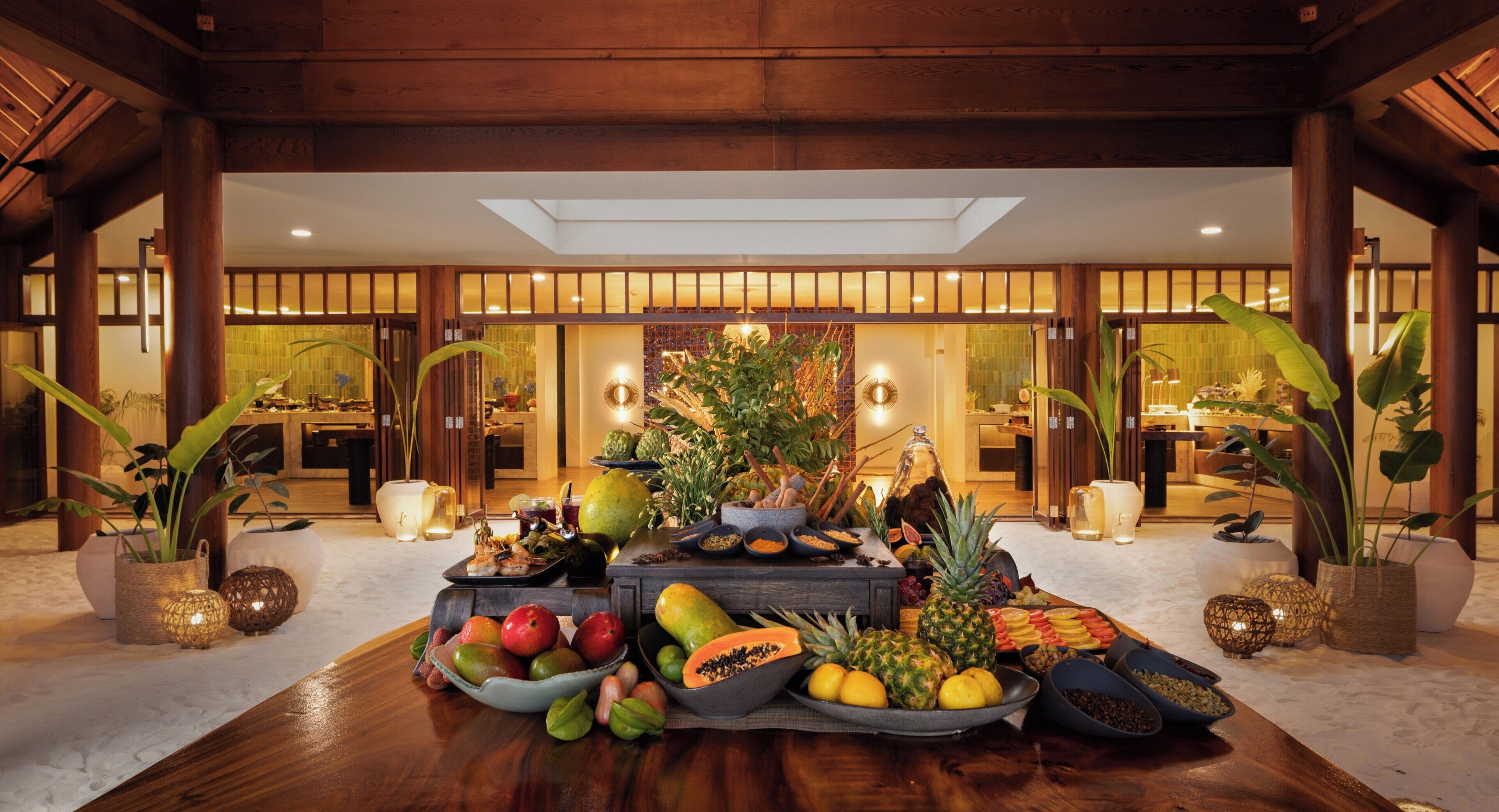 Uma área de refeições com uma mesa de madeira posta com frutas e um objeto decorativo.