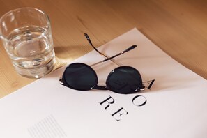 Um par de óculos de sol com armação e lentes pretas, apoiado em uma superfície branca com as letras 