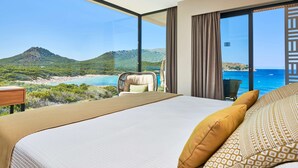 Quarto com uma cama grande, vista para uma praia e uma cadeira.
