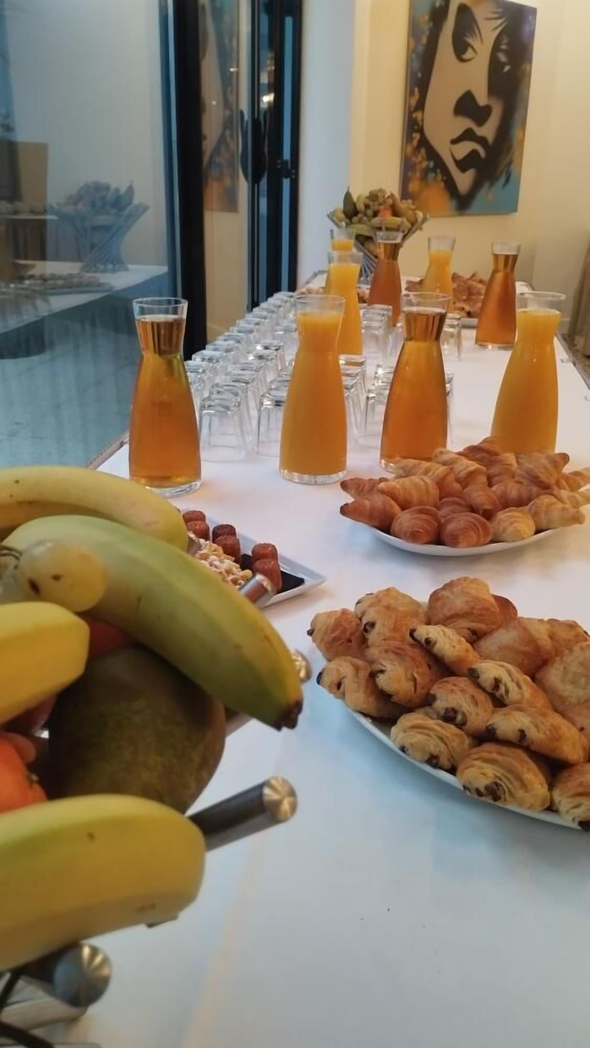 Um buffet de café da manhã com diversos pães, frutas e sucos.