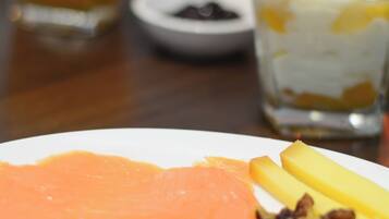 Um prato com salmão, abacaxi e nozes, e dois copos com suco de laranja e uma sobremesa.