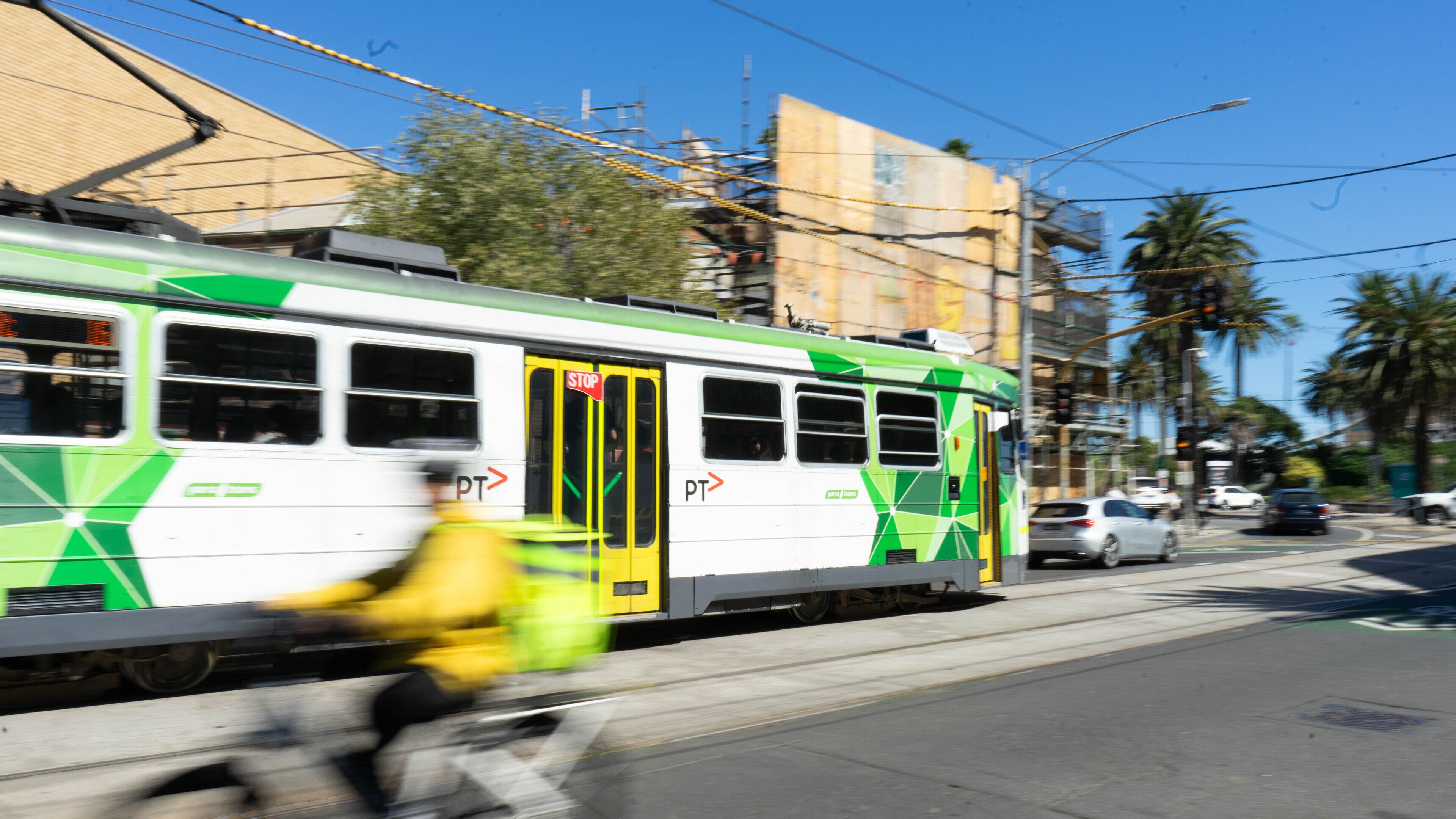 Um eléctrico com cores verde e branco, uma porta amarela e as letras 