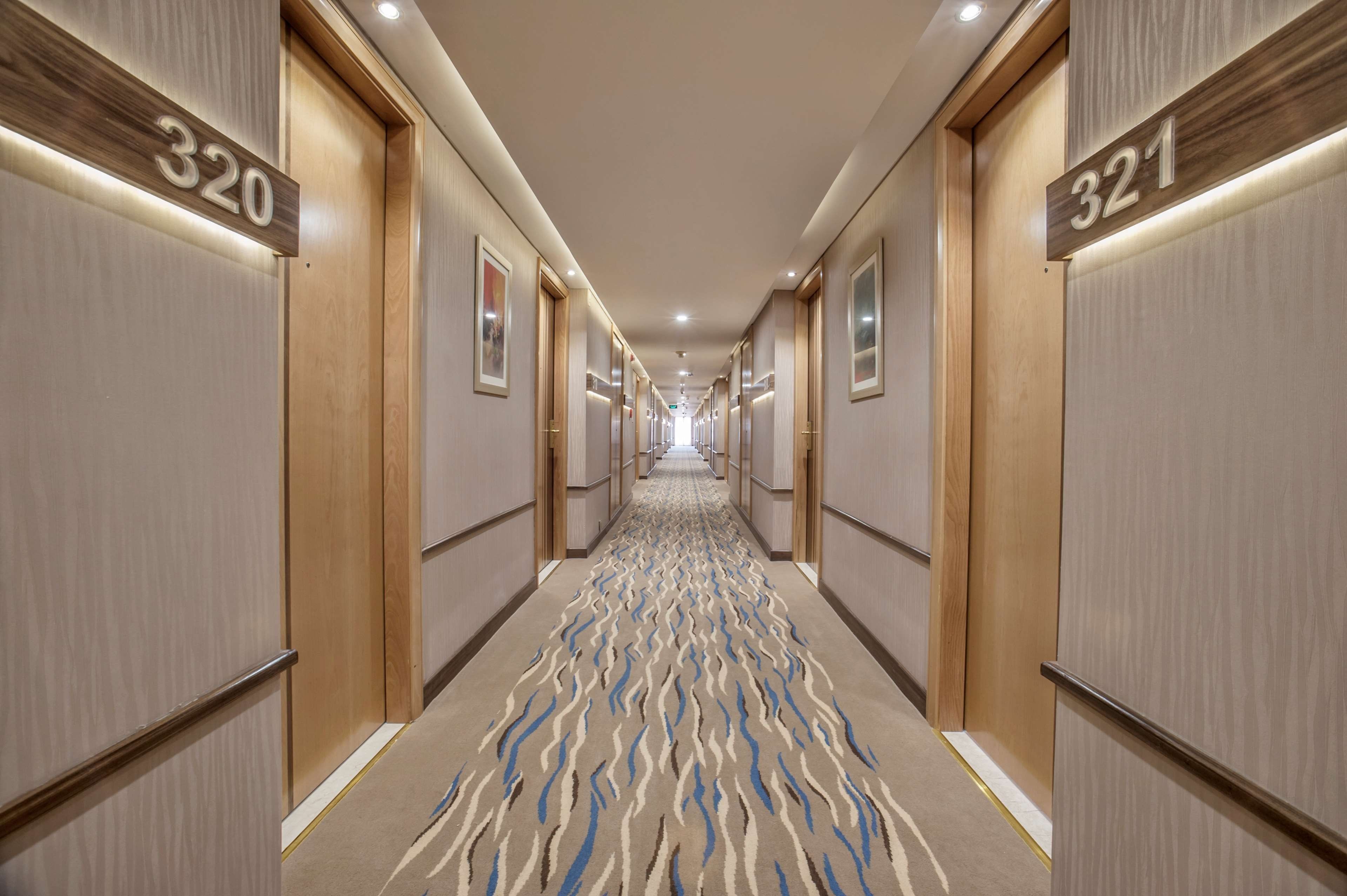 Corredor de hotel com portas numeradas 320 e 321, dando acesso aos quartos de hóspedes.