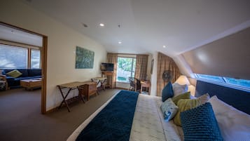 Quarto de hotel moderno com uma cama grande, uma escrivaninha, uma cadeira e uma televisão.