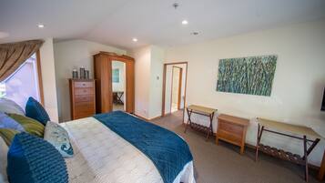 Um quarto com uma cama, cômoda de madeira, escrivaninha e uma cadeira.
