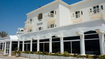 Um hotel branco com varandas e janelas grandes.