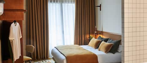Quarto de hotel com uma cama, uma cadeira, um guarda-roupa e uma casa de banho.