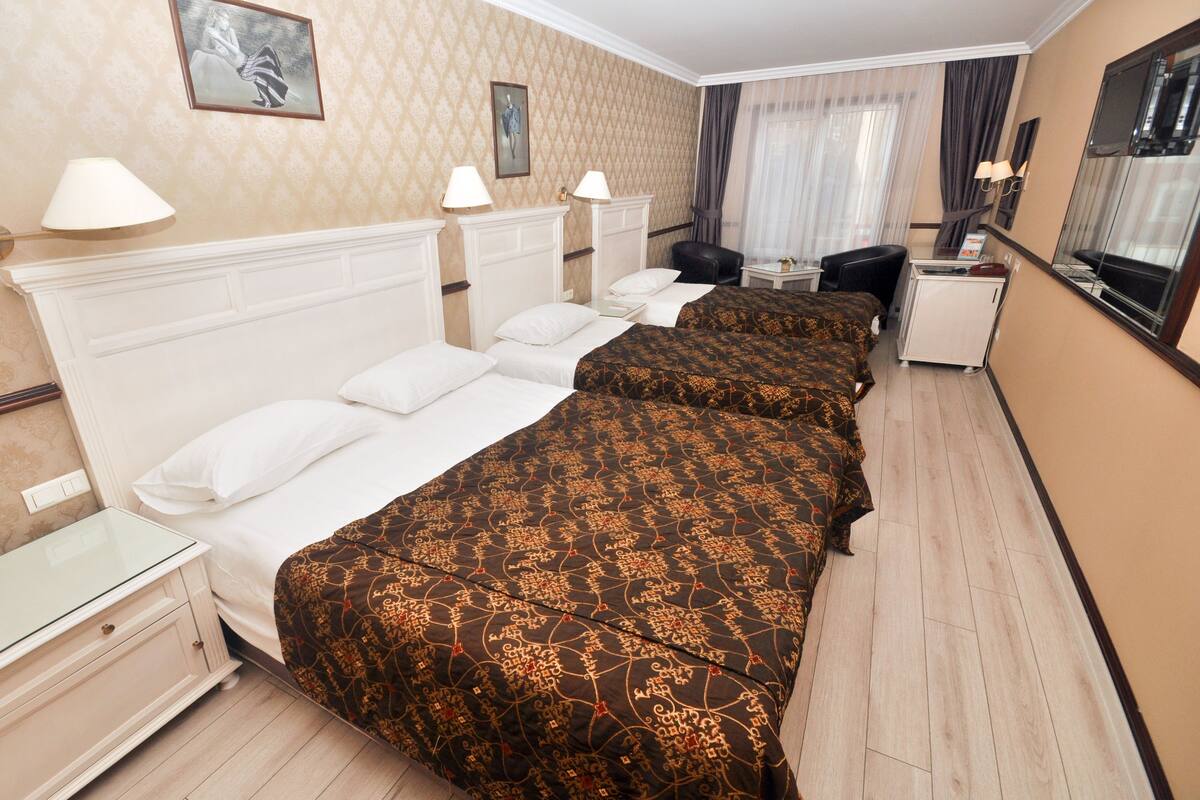 Quarto de hotel com uma cama grande, duas mesas de cabeceira, uma escrivaninha e um espelho.