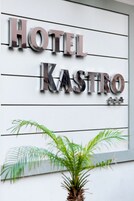 Placa de hotel com o nome 'HOTEL KASTRO' em letras metálicas.