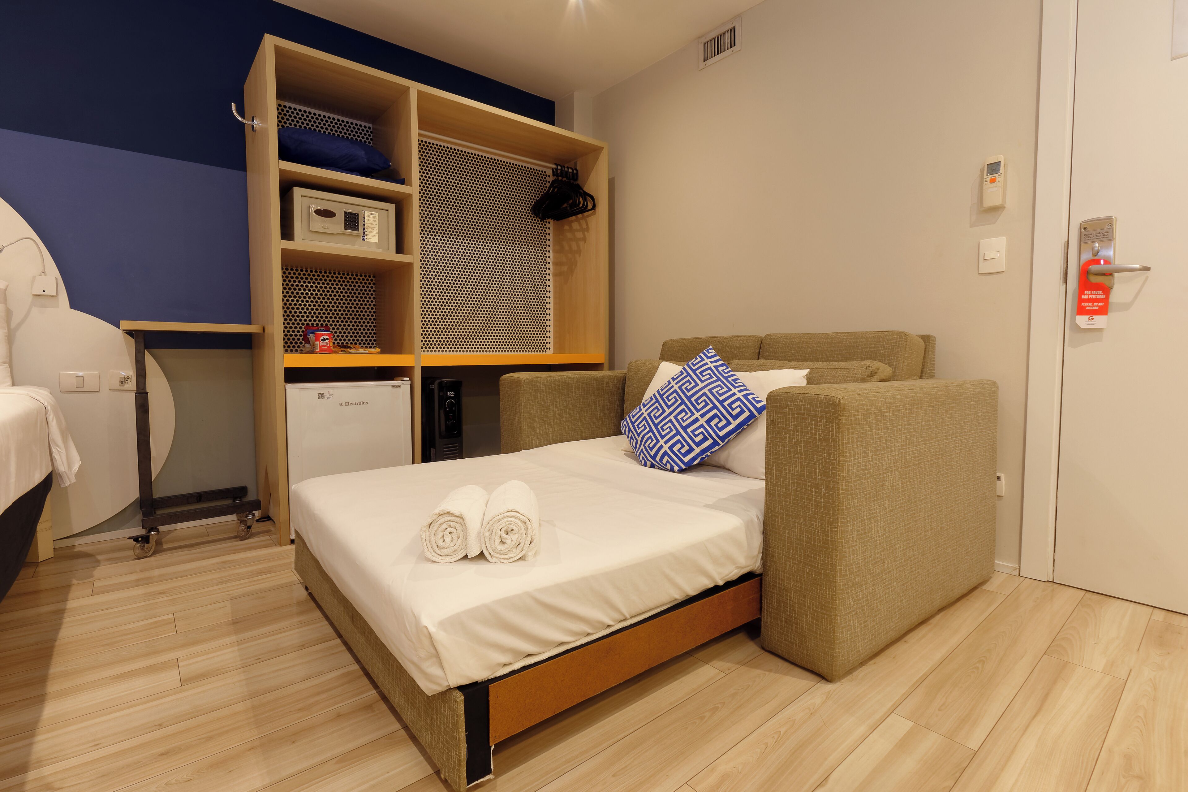 Quarto compacto com cama, guarda-roupa, escrivaninha e cadeira.