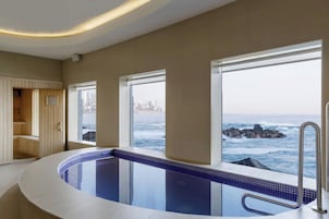 Piscina interior moderna com vista para o oceano.