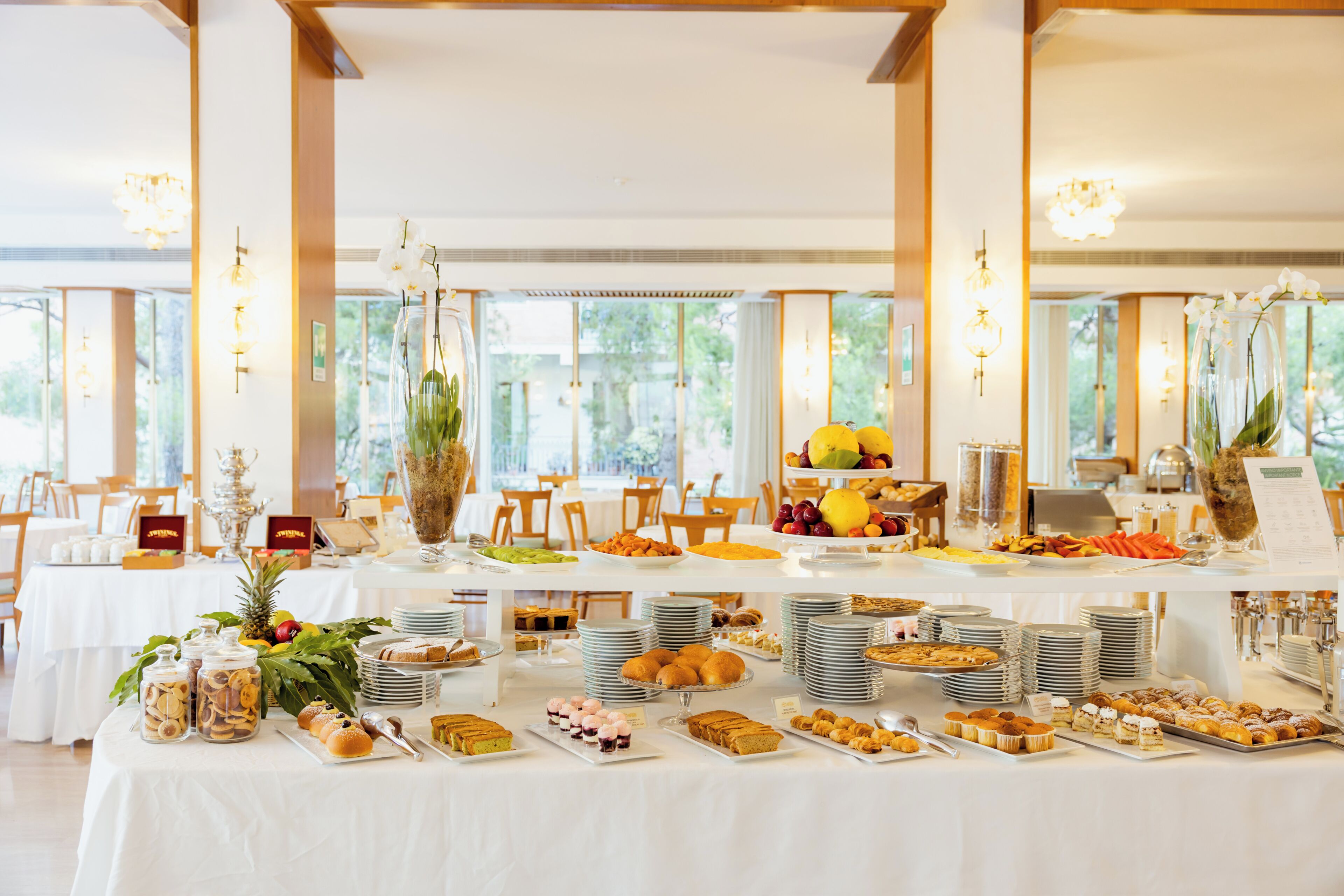 Uma mesa de buffet com diversos alimentos e um grande arranjo de flores.