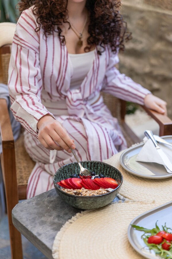 Uma pessoa sentada à mesa com uma tigela de comida, um prato de salada e um guardanapo.