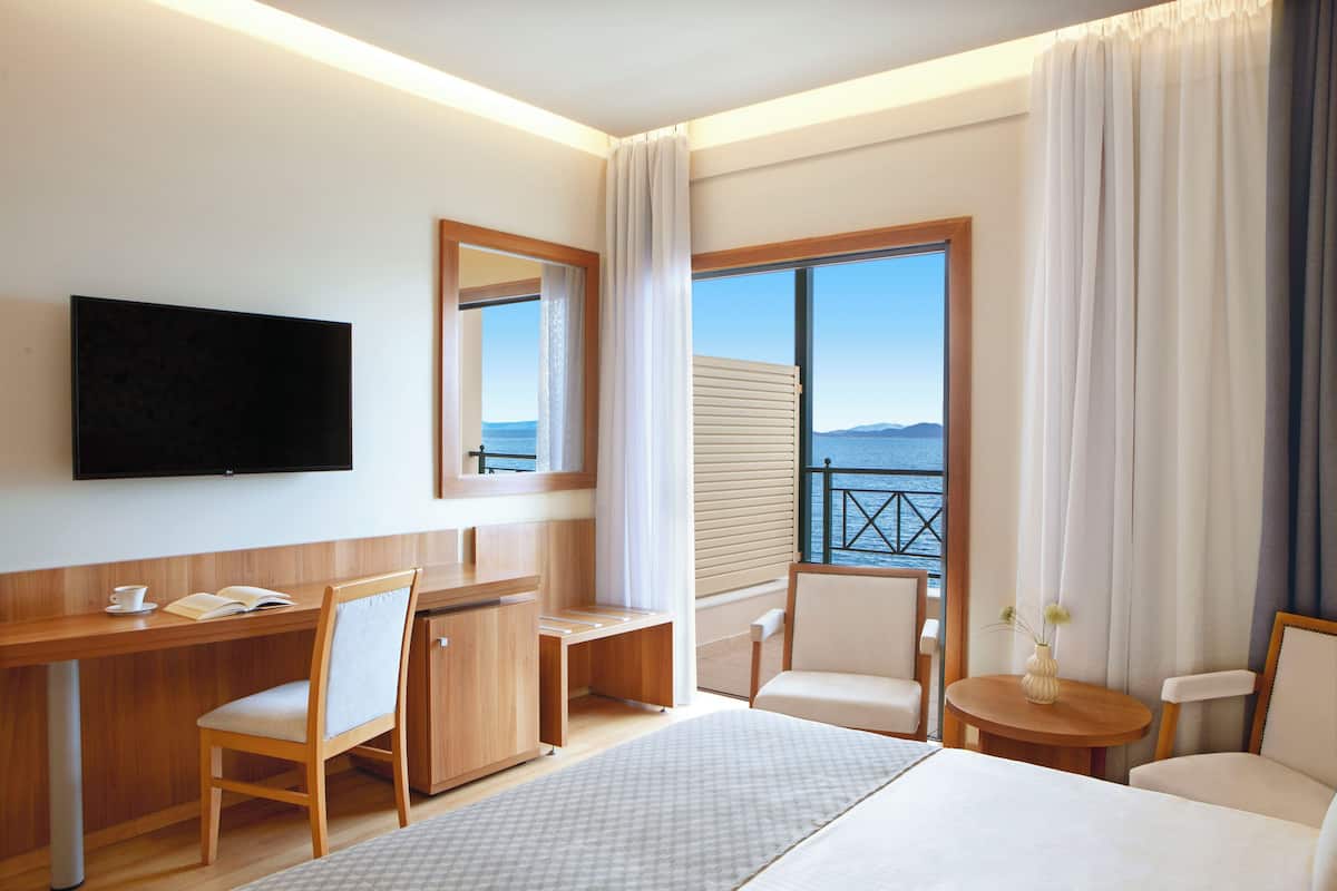 Quarto de hotel com uma cama, uma mesa de escritório, uma cadeira, uma mesinha e uma televisão.