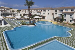 Um hotel com uma piscina grande, espreguiçadeiras e guarda-sóis.