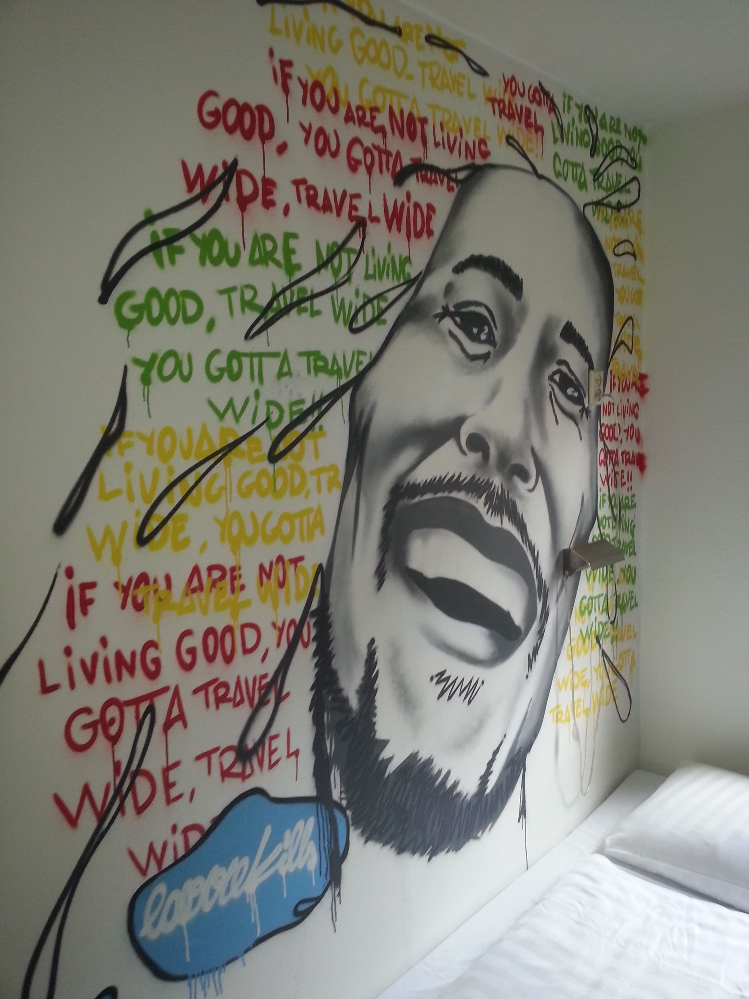 Paredes com texto em estilo de grafite e um retrato grande e estilizado.