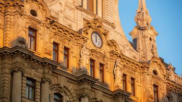 Um edifício histórico com detalhes arquitetônicos elaborados, incluindo uma torre do relógio imponente e estátuas.