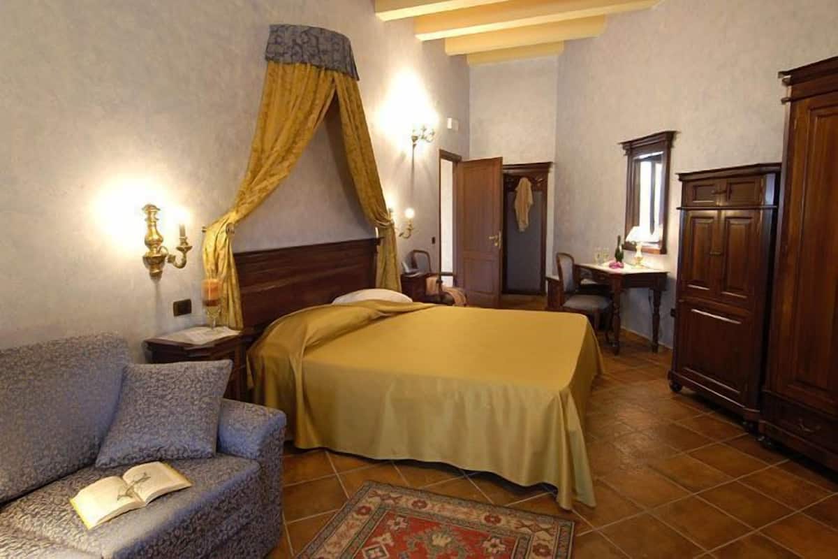Um quarto com cama, sofá, escrivaninha e guarda-roupa.