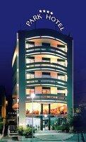 Um hotel de vários andares com fachada curva, janelas iluminadas e uma placa com a inscrição 'Park Hotel' no topo.