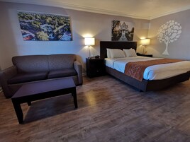 Quarto com cama, sofá, mesa de cabeceira e luminária na parede.