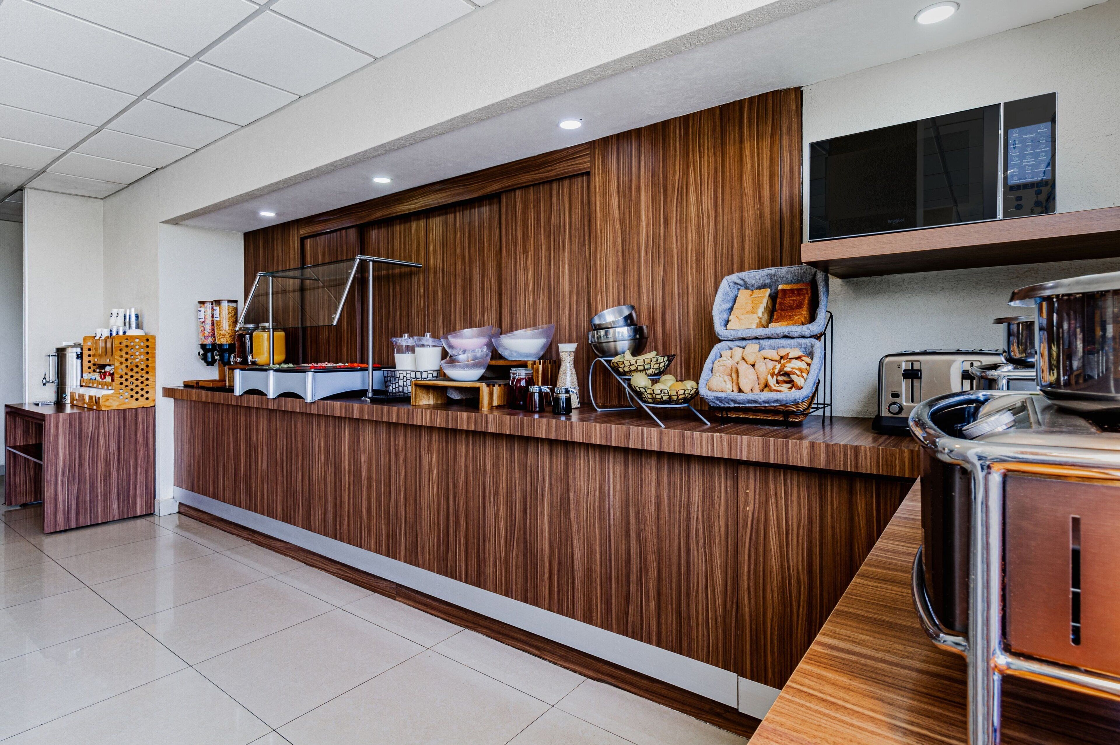 Cozinha moderna com bancada de madeira, diversos eletrodomésticos e micro-ondas.