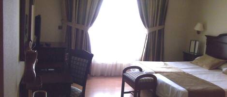Quarto de hotel com cama, escrivaninha e cadeira.