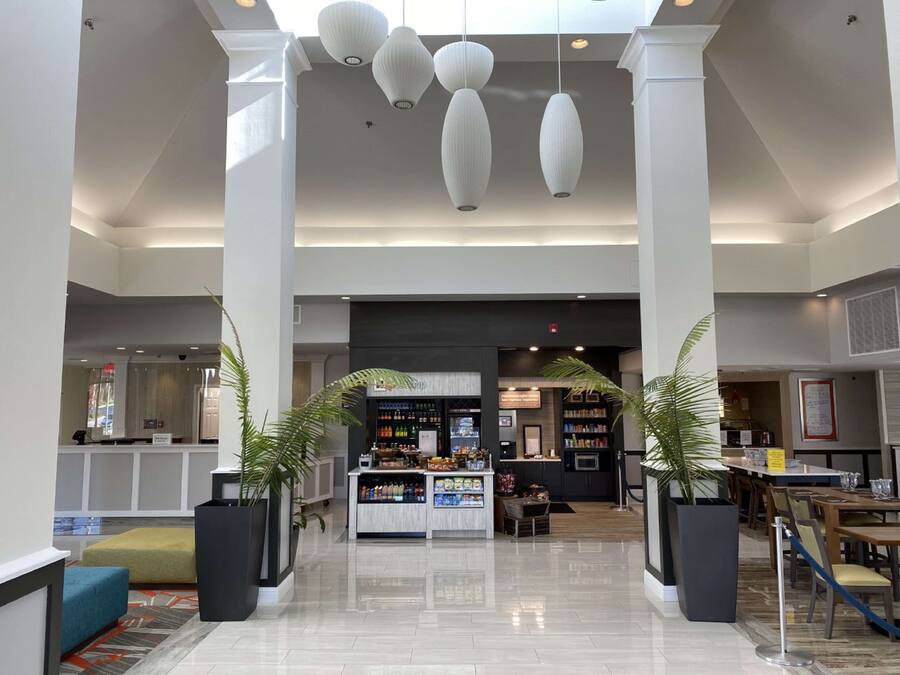 Um hall amplo com cafeteria, áreas de estar e balcão de recepção.
